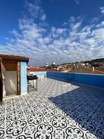 Terraço no telhado com ladrilhos estampados, uma mesa e cadeiras.