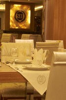 Ambiente de restaurante com louças brancas, incluindo pratos, copos e guardanapos.