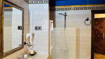 Casa de banho com lavatório, espelho, secador de cabelo e chuveiro com porta-toalhas.