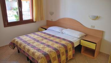 Quarto com cama, duas mesas de cabeceira, janela com cortinas e luminária na parede.