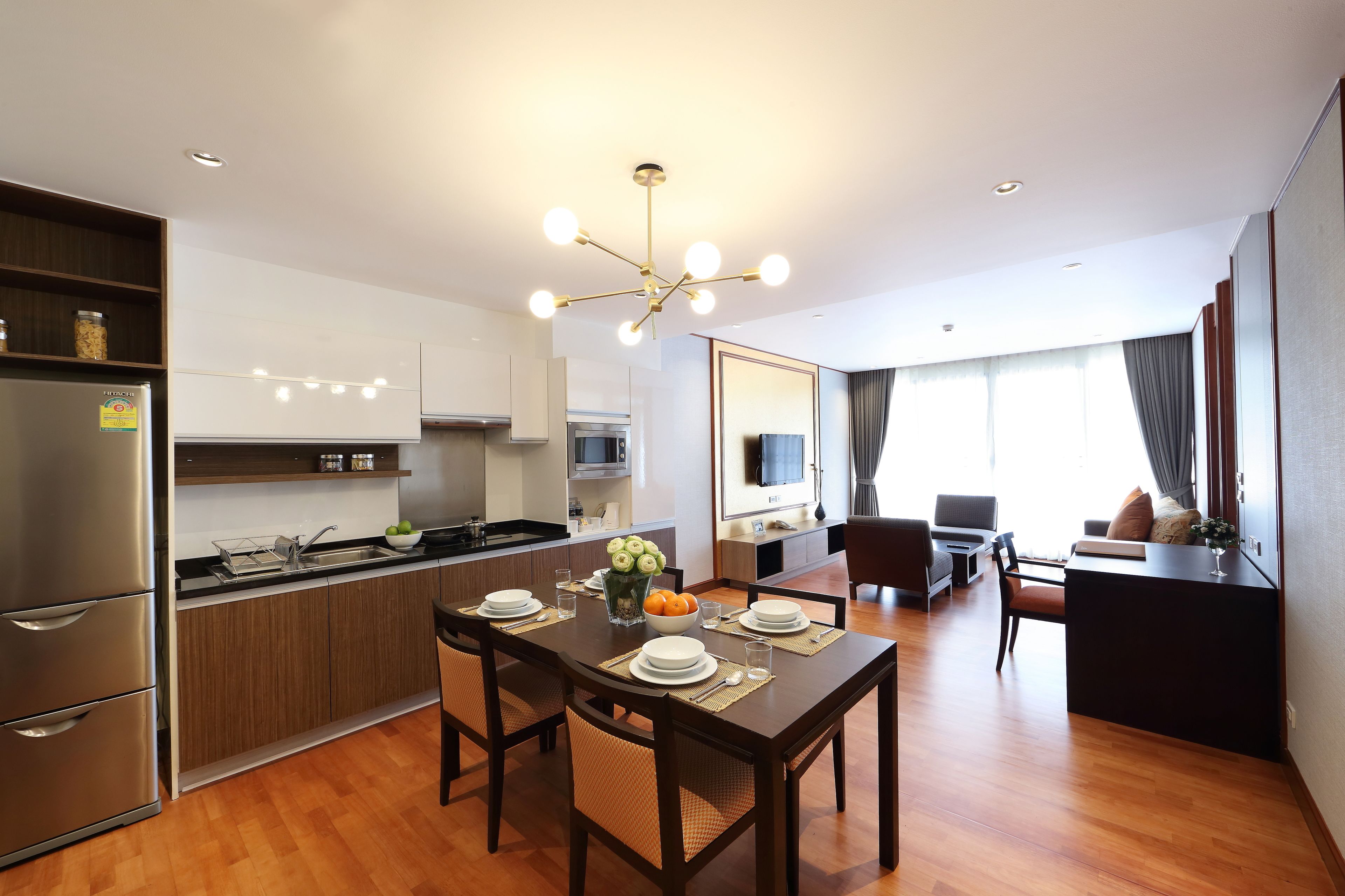 Cozinha moderna com área de refeições, piso de madeira e um candelabro.