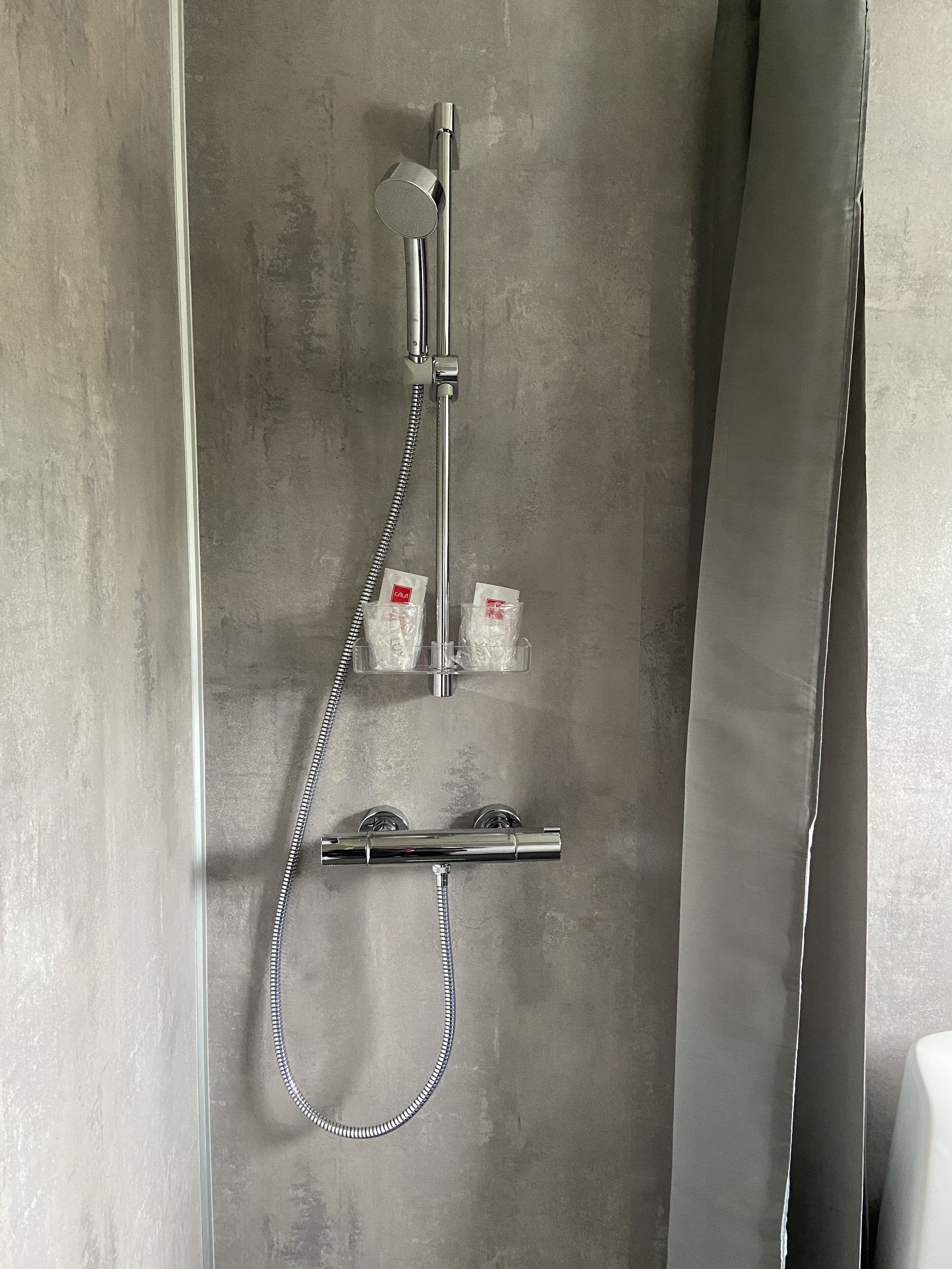 Um chuveiro moderno com um chuveiro de mão, torneira embutida na parede e um acessório de chuveiro manual.