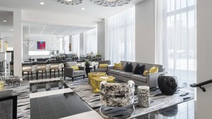 Uma sala de estar espaçosa com design moderno, com um sofá grande, uma mesa de centro e um espaço de jantar com cadeiras.