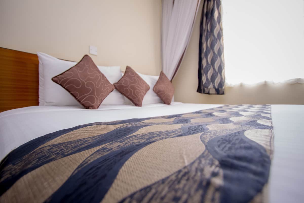 Cama bem arrumada com almofadas estampadas e manta decorativa.
