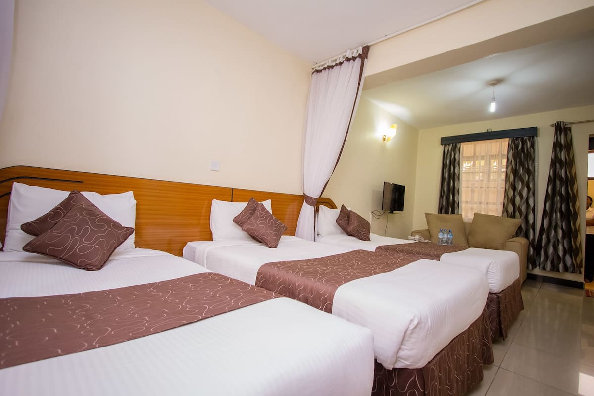 Quarto de hotel com quatro camas, uma mesa de jantar e área de estar separada.