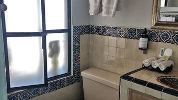 Casa de banho com sanita, pia, espelho e janela com vidro jateado.