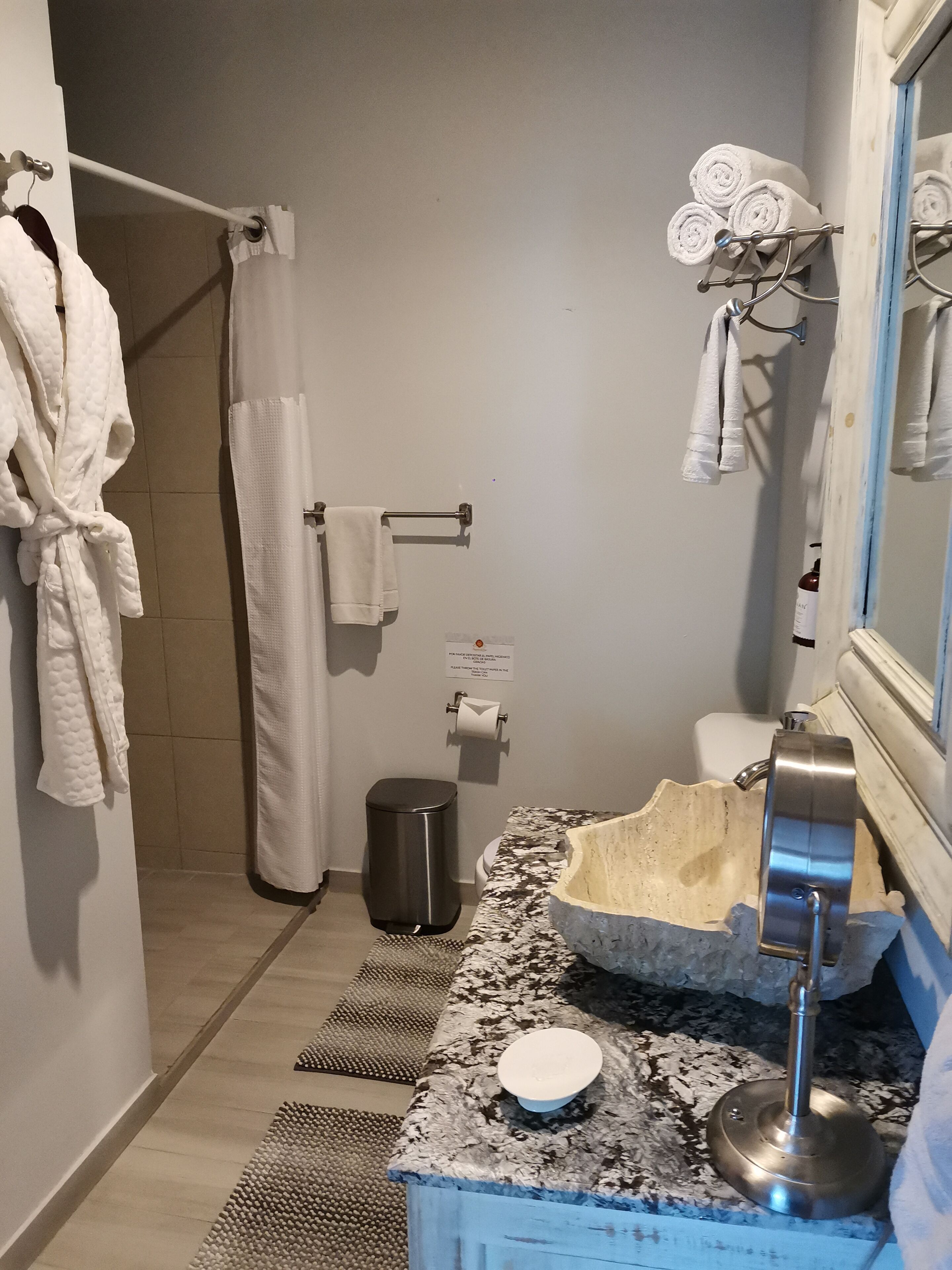 Casa de banho com chuveiro, sanita, lavatório e suporte para toalhas.
