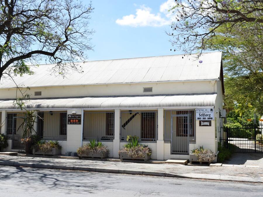 Um edifício de dois andares com telhado de chapa metálica, várias janelas e uma placa anunciando um chalé de aluguel por temporada.
