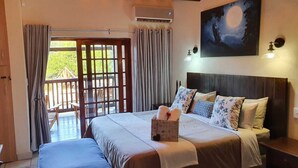 Quarto com uma cama grande, mesa de cabeceira, pintura da lua e vista para o exterior.