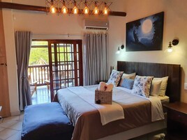 Quarto com uma cama grande, mesa de cabeceira, pintura da lua e vista para o exterior.