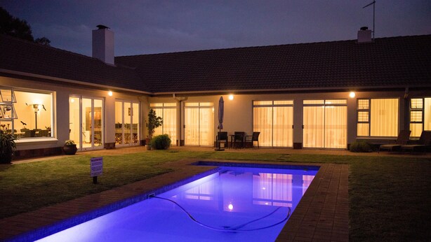 Um imóvel residencial com piscina, varanda coberta e entrada bem iluminada.
