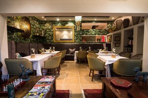 Uma sala de jantar com mesas, cadeiras e objetos decorativos.