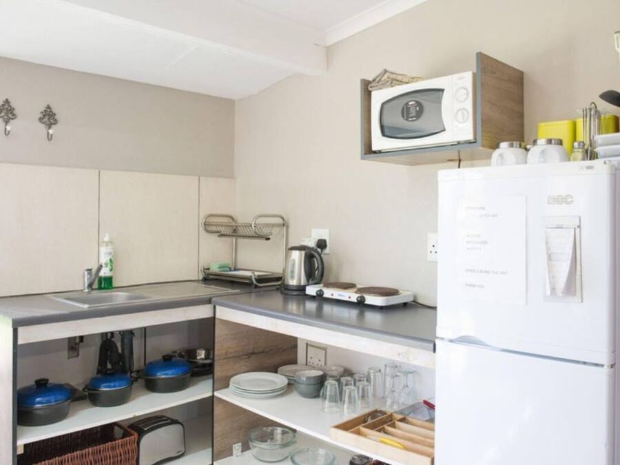 Uma cozinha compacta com micro-ondas, geladeira branca e diversos utensílios e eletrodomésticos.