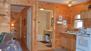 Interior de uma cabana de madeira com quarto, banheiro e cozinha.