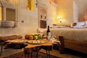 Um quarto rústico com uma cama, uma mesa de madeira e paredes de pedra.