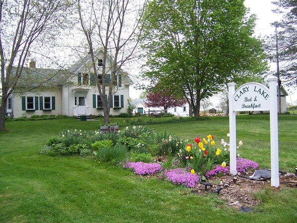 Placa de identificação do Clary Lake Bed & Breakfast, com um jardim bem cuidado à frente.