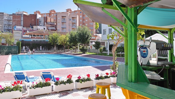 Piscina com espreguiçadeiras e área de bar com refrigerador de Pepsi.