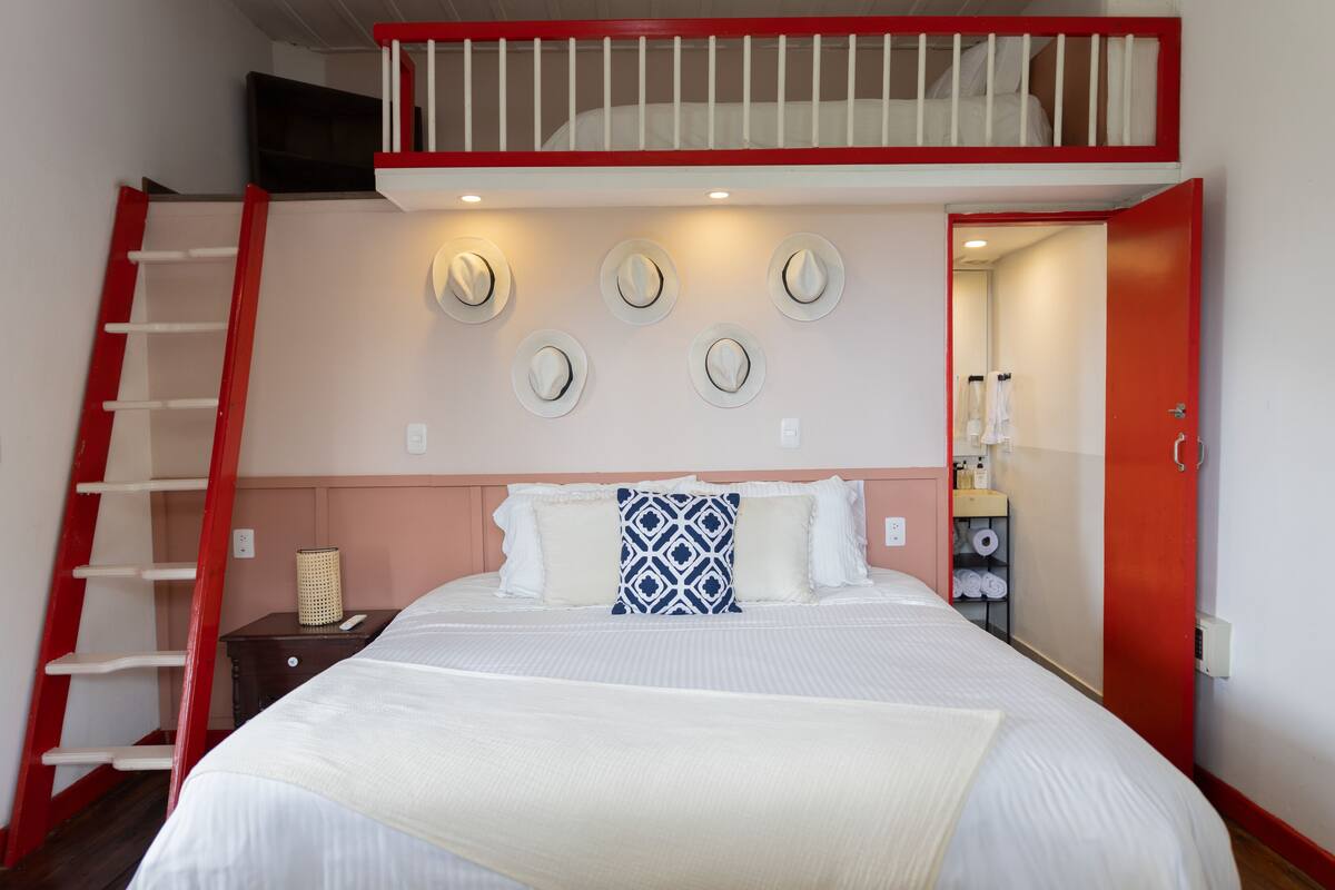 Um quarto com beliche, escada, mesa de cabeceira e guarda-roupa.