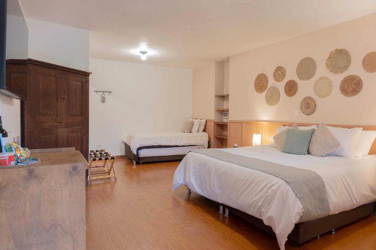 Quarto com duas camas, soalho de madeira, guarda-roupa e decorações nas paredes.