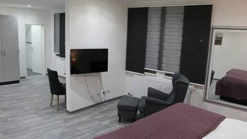 Quarto de hotel moderno com uma cama, uma televisão, uma escrivaninha e uma cadeira.