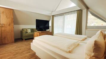 Quarto de hotel com cama, televisão, sofá e guarda-roupa.