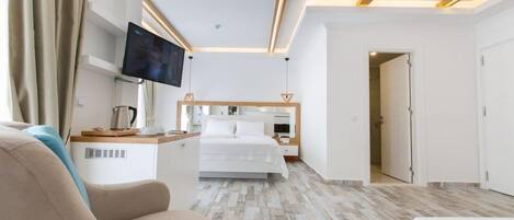Quarto de hotel moderno com cama, televisão, escrivaninha e área de estar.
