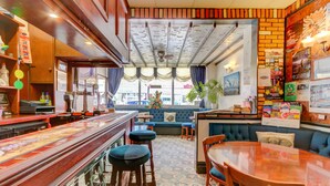 Uma área de bar com banquetas, balcão e um espaço de estar com sofá e cadeiras.