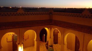 Um pátio com arcos e vista da cidade ao entardecer.