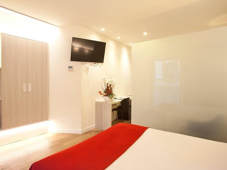 Quarto de hotel moderno com uma cama grande, uma escrivaninha, uma televisão e um guarda-roupa.