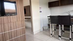 Cozinha moderna com televisão embutida, armários de madeira e área de refeições com cadeiras.