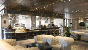 Um lobby de hotel moderno com área de bar, sofás de couro e carpete estampado.