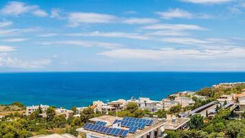 Uma vila costeira com vista para o mar, edifícios com painéis solares e um céu claro.