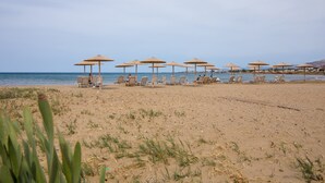 Uma praia com fileiras de guarda-sóis e espreguiçadeiras voltadas para o mar.