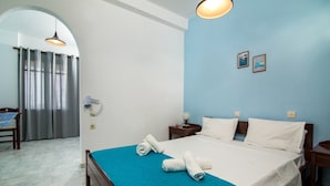 Quarto de hotel com cama, mesa de cabeceira, luminária, secador de cabelo e janela com cortinas.