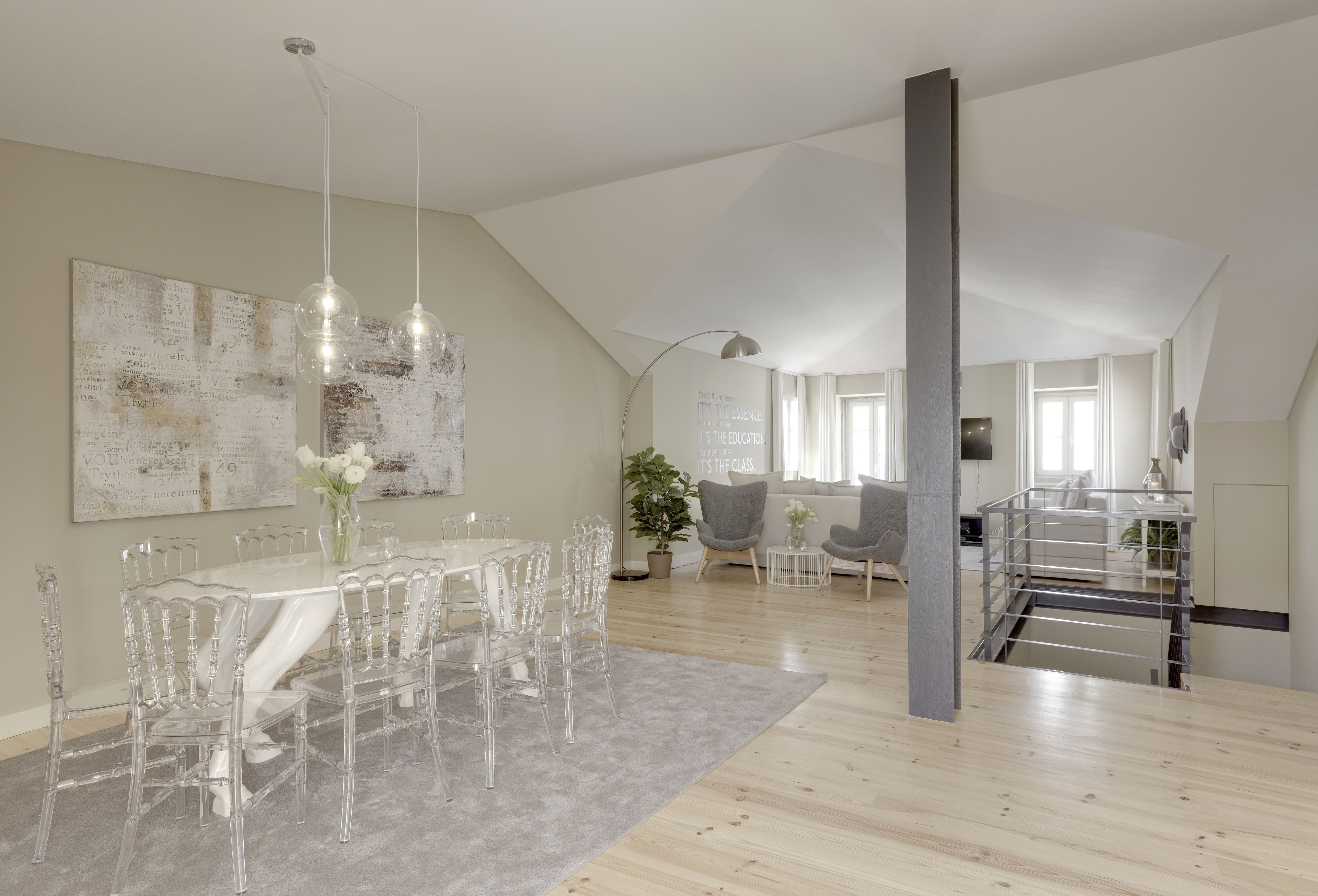 Uma sala de estar ampla com uma mesa de jantar, cadeiras transparentes e uma escada moderna.