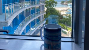 Um edifício moderno com varanda curva e vista para a área costeira.