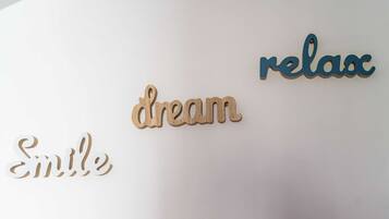 Três letras de madeira recortadas em uma parede: 'dream', 'relax' e 'smile'.