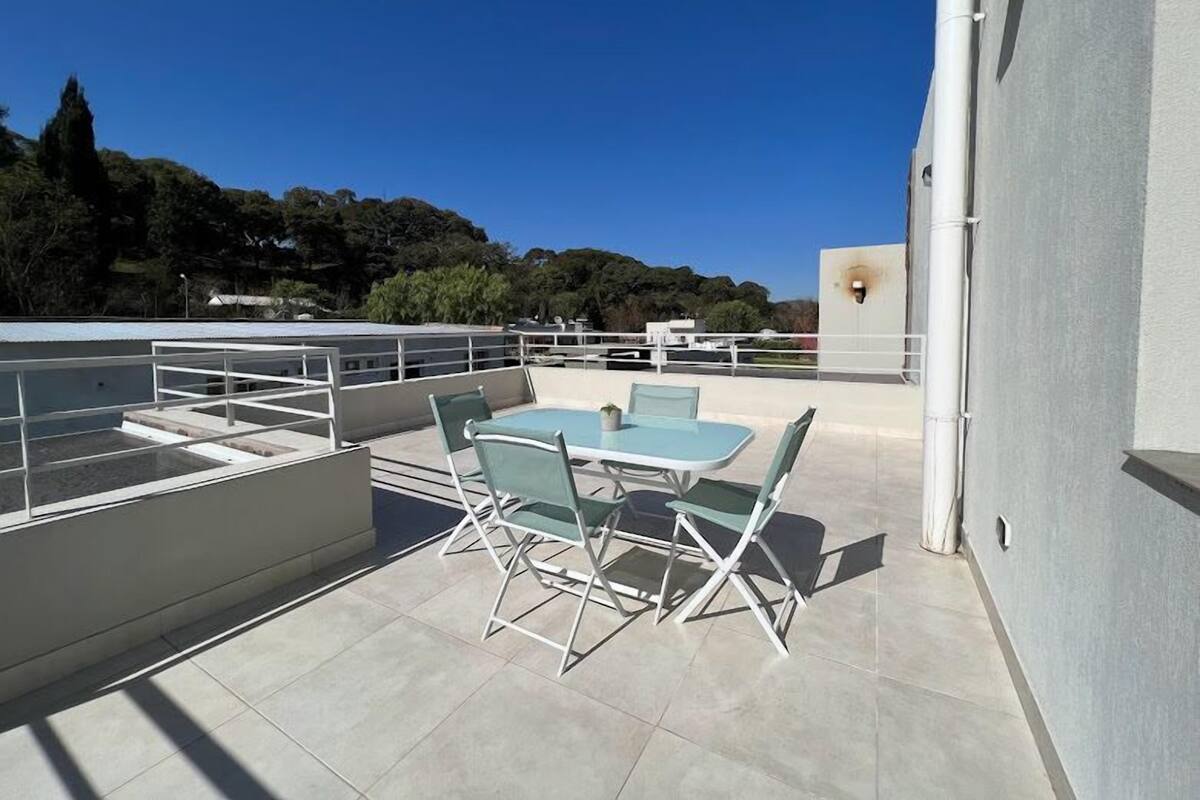 Terraço no telhado com mesa de bilhar, cadeiras e vista para a paisagem ao redor.