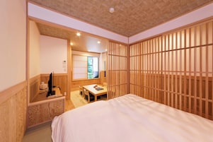 Um quarto tradicional em estilo japonês com cama, escrivaninha de madeira e porta deslizante.