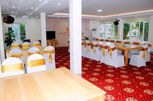 Sala de conferências com grande mesa e cadeiras, carpete estampado em vermelho e amplas janelas com vegetação lá fora.