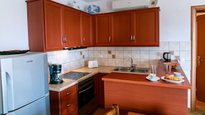 Uma cozinha compacta com armários de madeira, geladeira, cafeteira e torradeira.