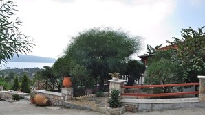 Um jardim com plantas em vasos, um muro de pedra e vista para uma montanha distante.