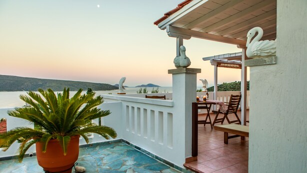 Um terraço com planta em vaso, área de estar externa e vista para o mar.