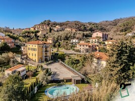 Zona residencial com um edifício grande com várias varandas, piscina e um cenário montanhoso.