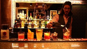 Um bar com uma variedade de garrafas e copos nas prateleiras.