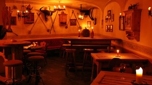 Um restaurante com iluminação suave, mesas e bancos de madeira, velas e decoração rústica.