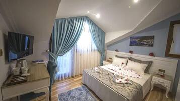 Quarto com cama, escrivaninha, cadeira, televisão, janela com cortinas e um quadro na parede.