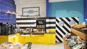 Uma cozinha moderna com armários amarelos, painel de fundo preto e branco e uma exposição de frutas.