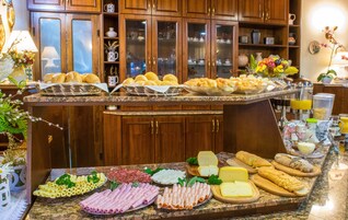 Buffet com diversos alimentos, incluindo pão, queijo e frios.
