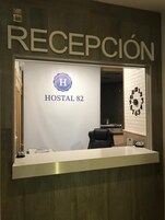 Uma mesa de recepção com uma placa que diz "RECEPCIÓN" e "HOSTAL 82".